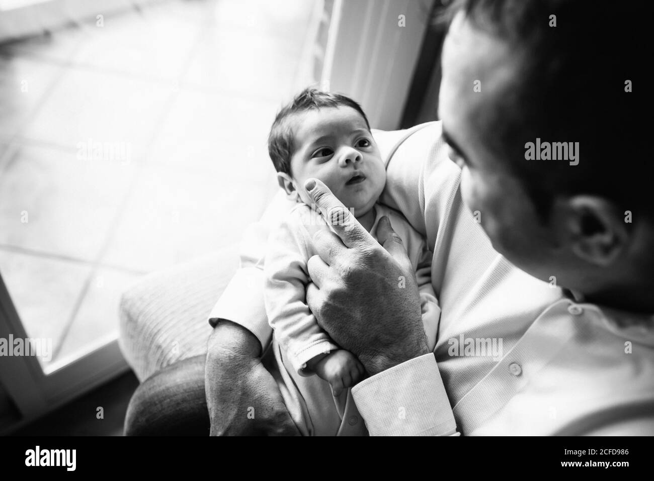 father hugging cute little baby looking away at home Stock Photo - Alamy