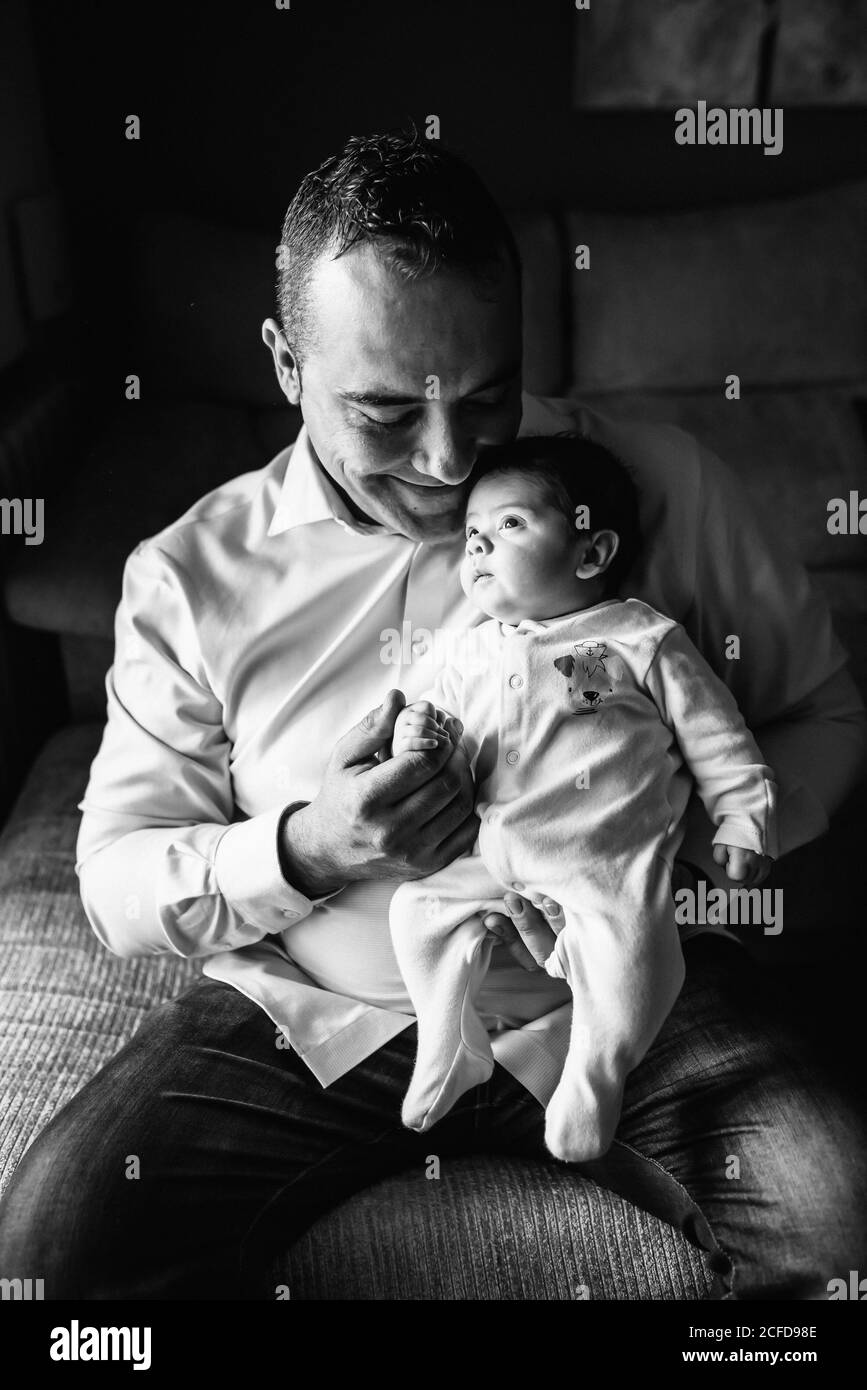 father hugging cute little baby looking away at home Stock Photo - Alamy