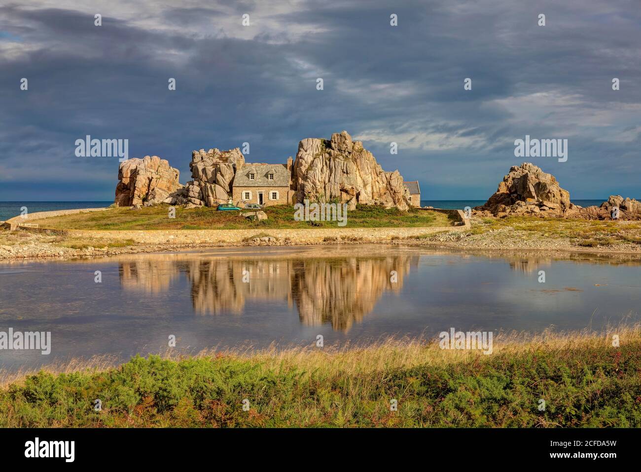 House between two rocks with reflection in a small lake, La Maison du ...