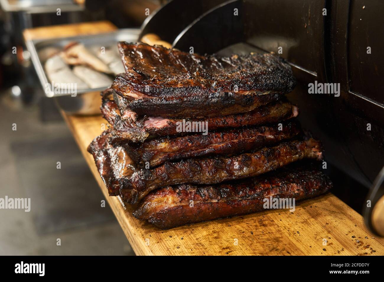 Composed stack of grilled juicy ribs on cutting board near barbecue ...