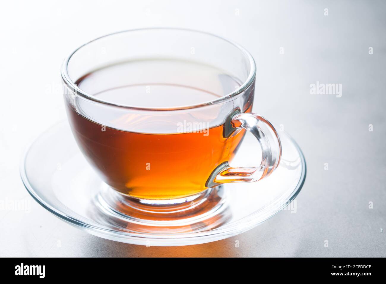 Closeup glass cup of aromatic hot tea placed on saucer on table in ...