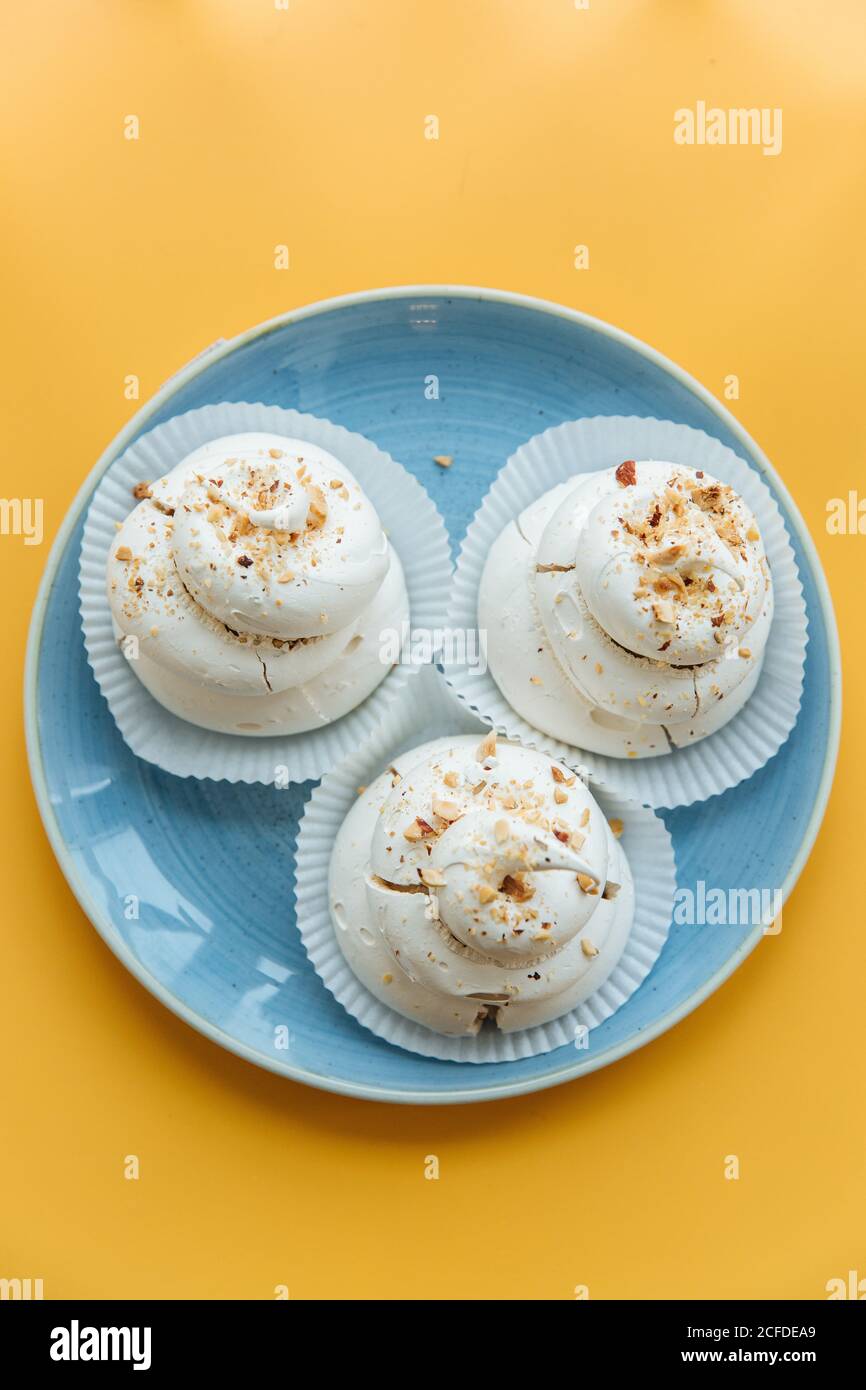 Top view of creamy meringue decorated with pieces of nuts in blue ...