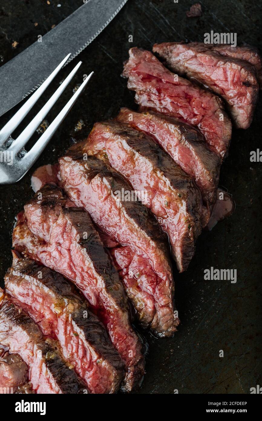 Top view of medium rare slices steak on table with fork and knife in ...