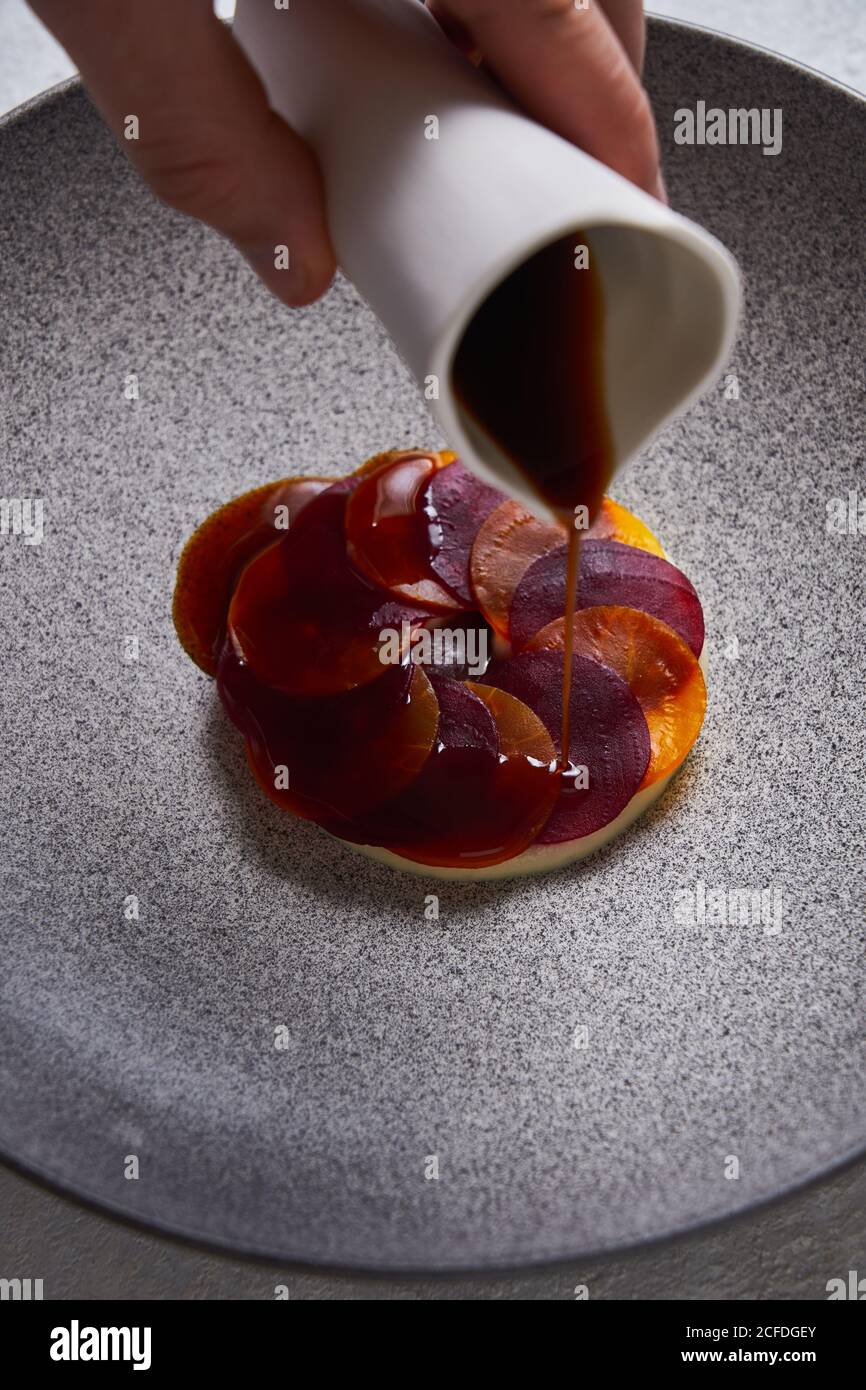 From above anonymous person adding sauce to delectable dish made of ...