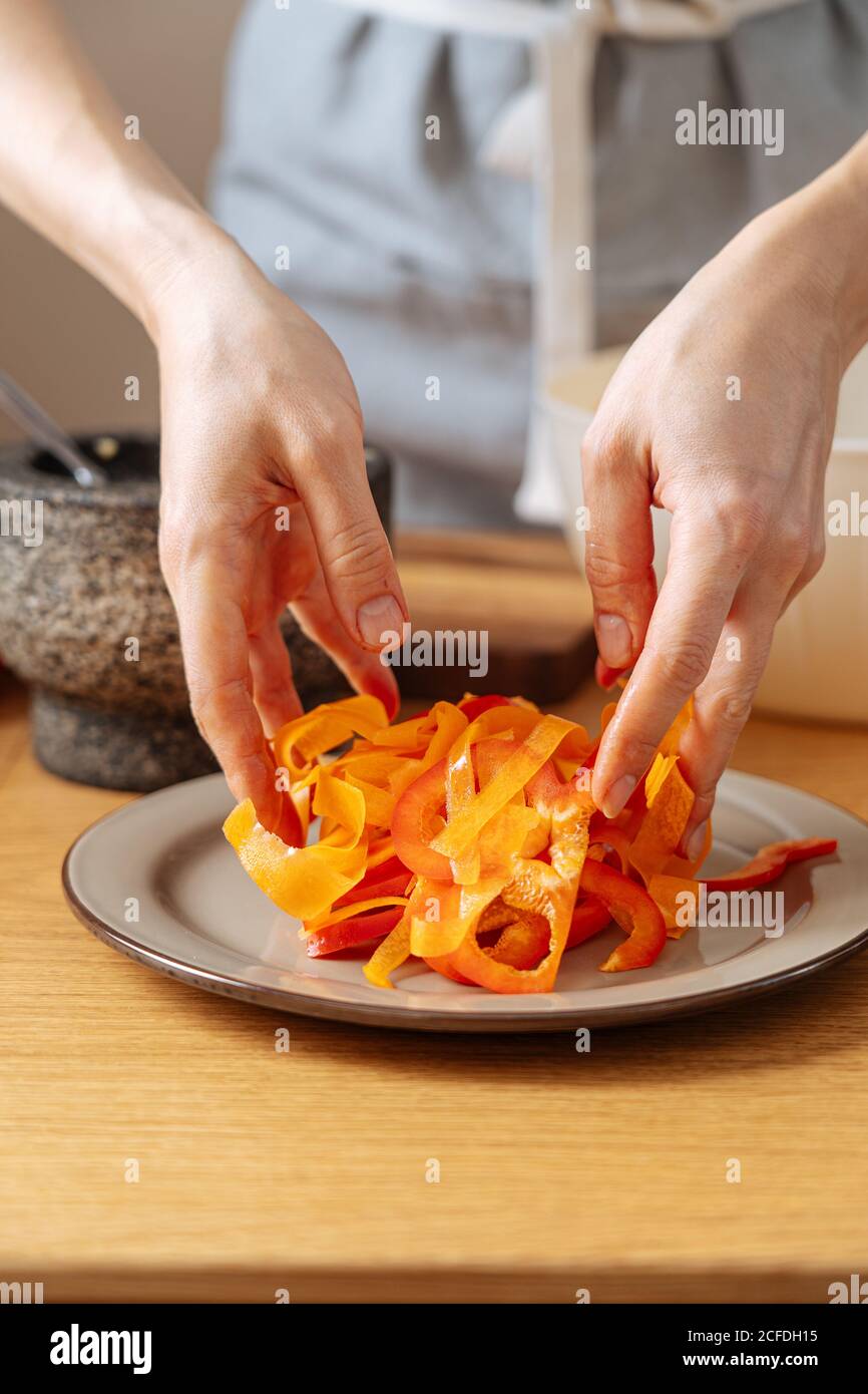 anonymous person mixing cut fresh vegetables on plate while cooking ...