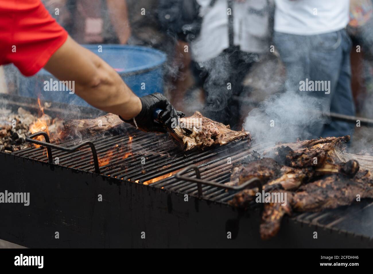 From above of crop chef turning fried chicken with smoke on grill in ...