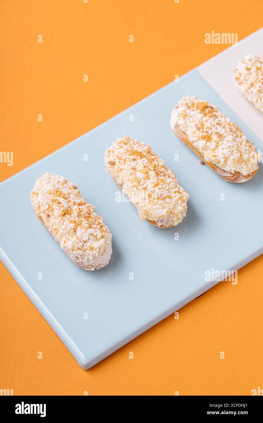 From above yummy soft eclairs with white creamy icing placed in line on ...