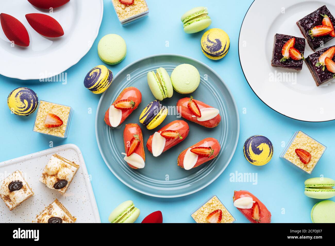 Top view of assorted cookies and cakes placed on plates on blue ...