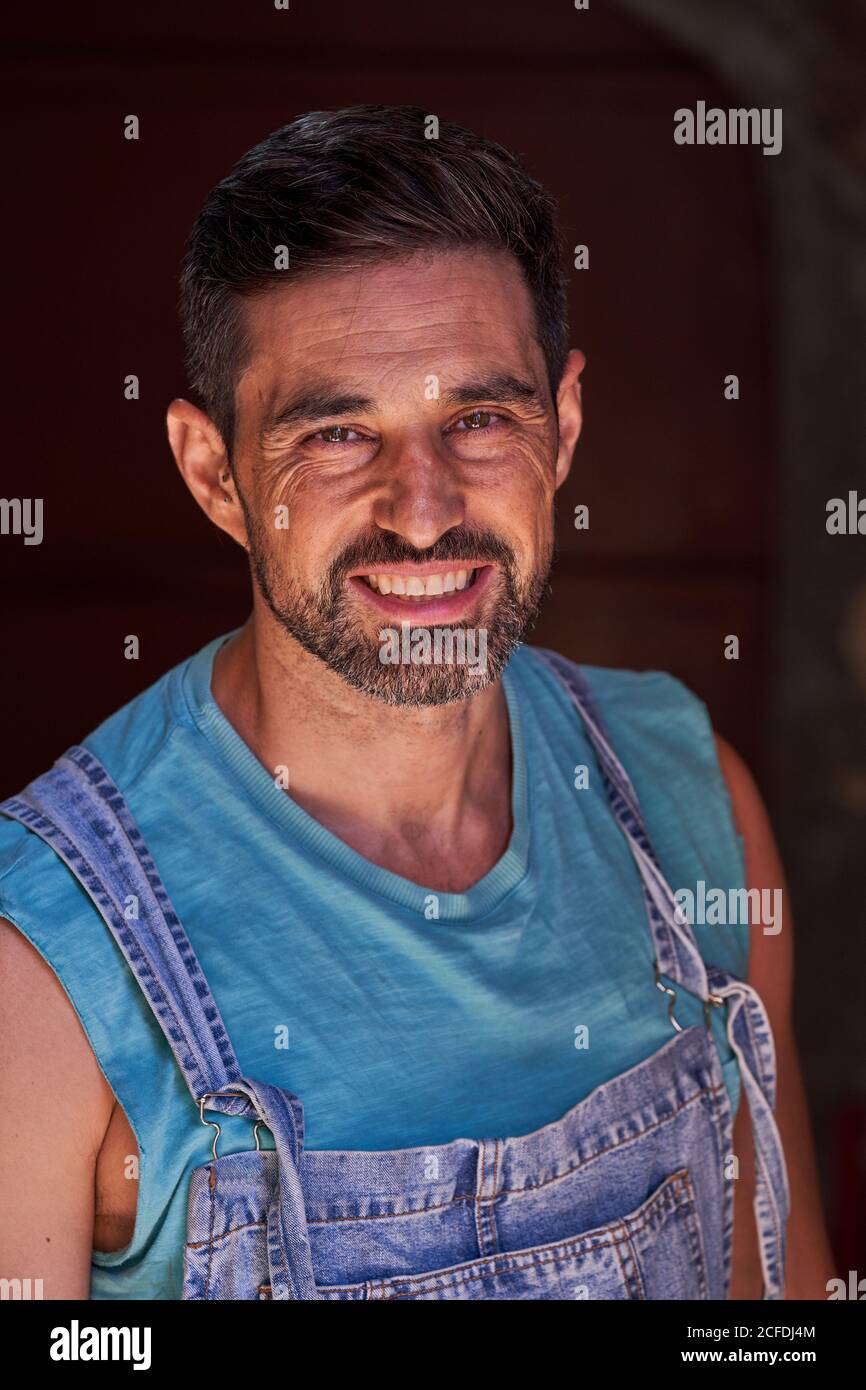 Happy smiling bearded middle aged workman wearing blue shirt and jeans ...