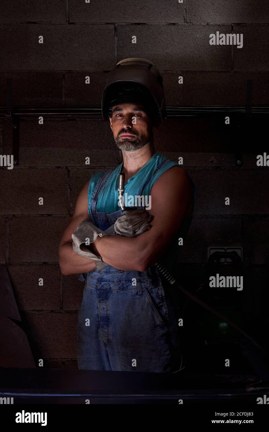 Serious confident bearded workman in welding helmet on head wearing ...