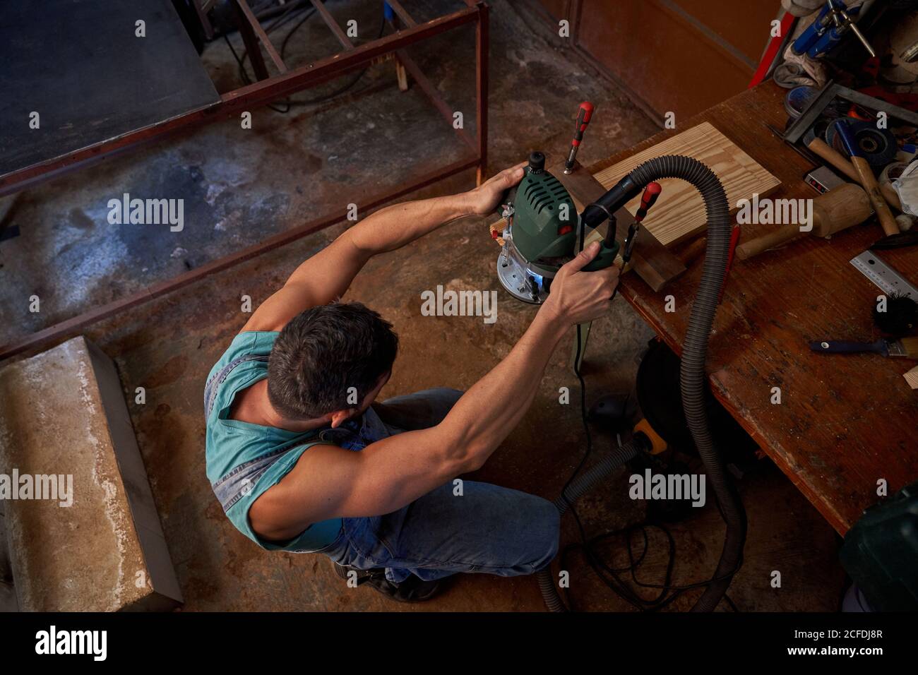 From above of male worker using milling machine while processing wooden ...