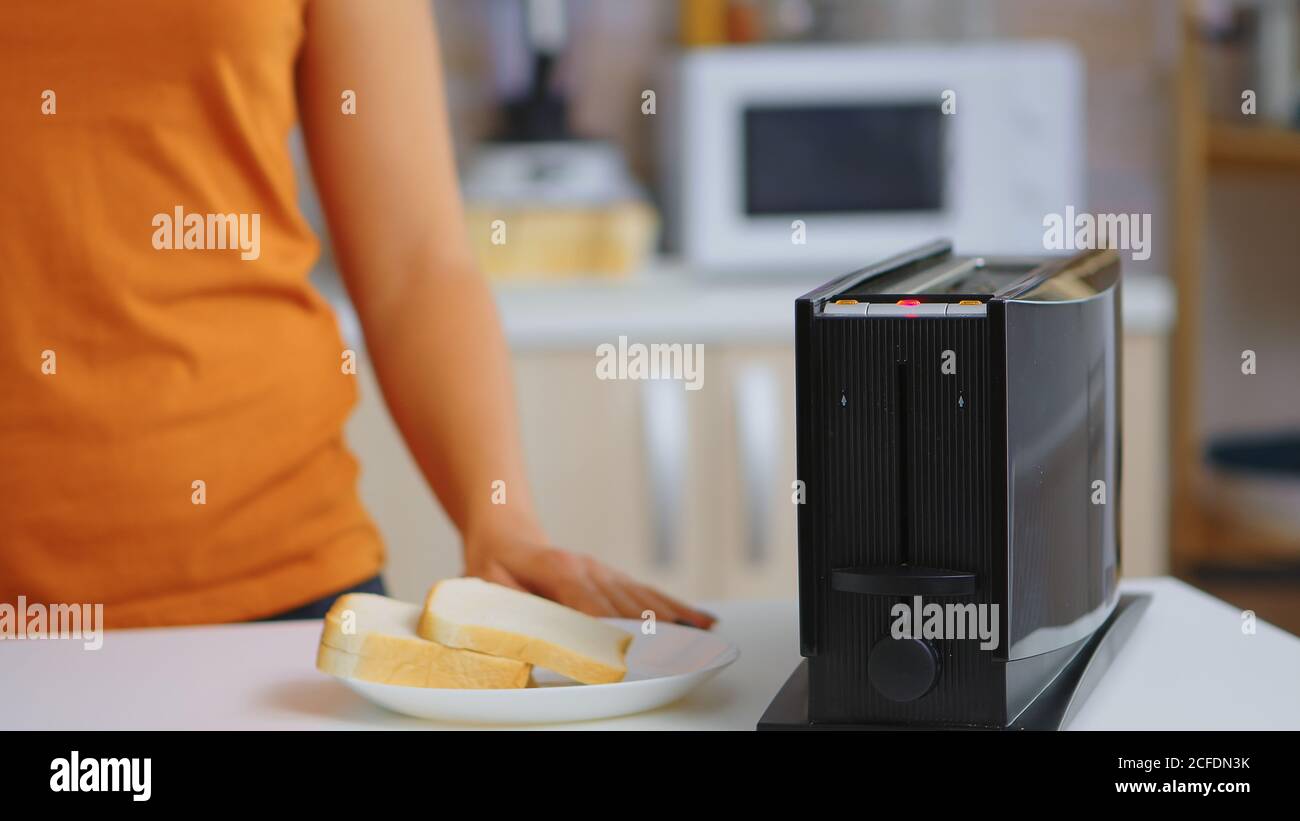 Woman waiting for roasted bread to pop from electric toaster. Housewife ...