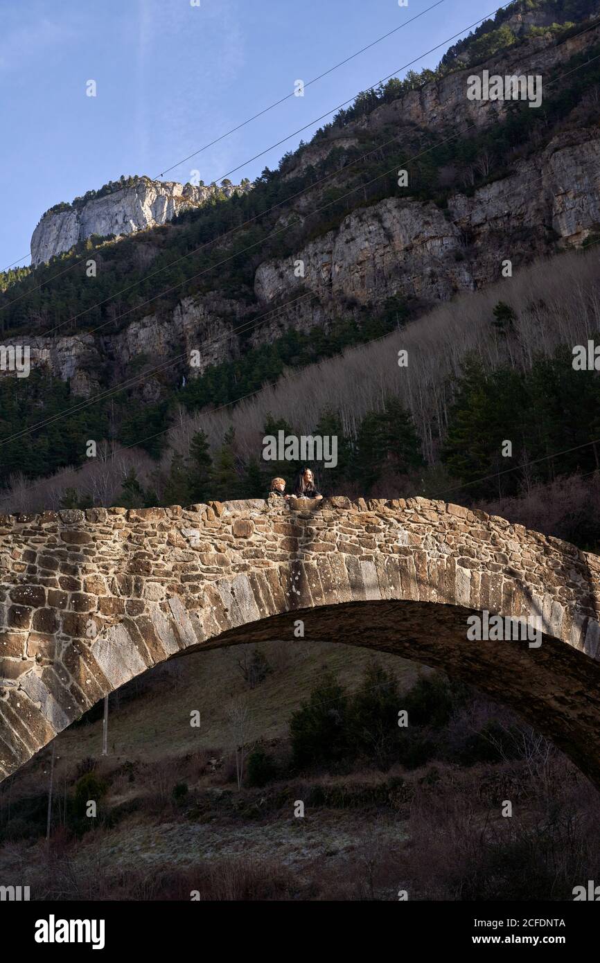 Traveling Woman with kid moving though ancient arch bridge to forest ...