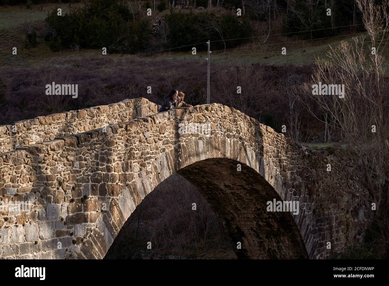 Traveling Woman with kid moving though ancient arch bridge to forest ...