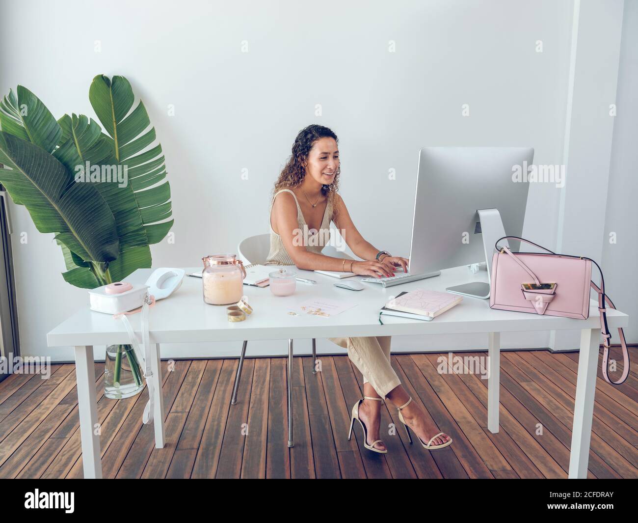 Cute young Woman in elegant outfit smiling and typing on computer ...