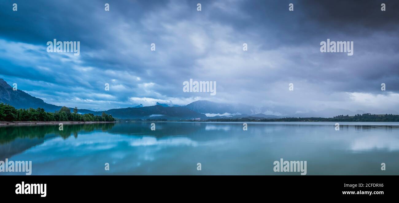 A panoramic image of lake Forggensee with mountains in the background ...