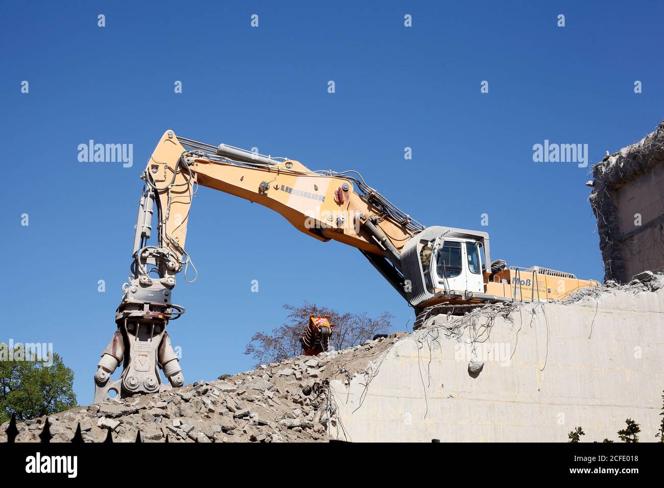 Demolition excavator on the wreckage of a demolished air-raid shelter ...