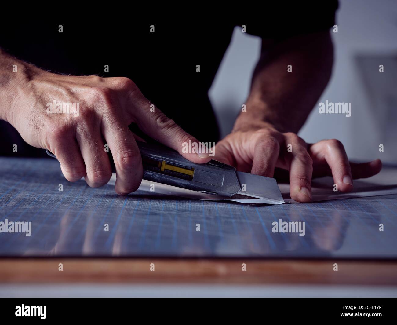 Crop professional man cutting paper sheets with special sharp knife on ...