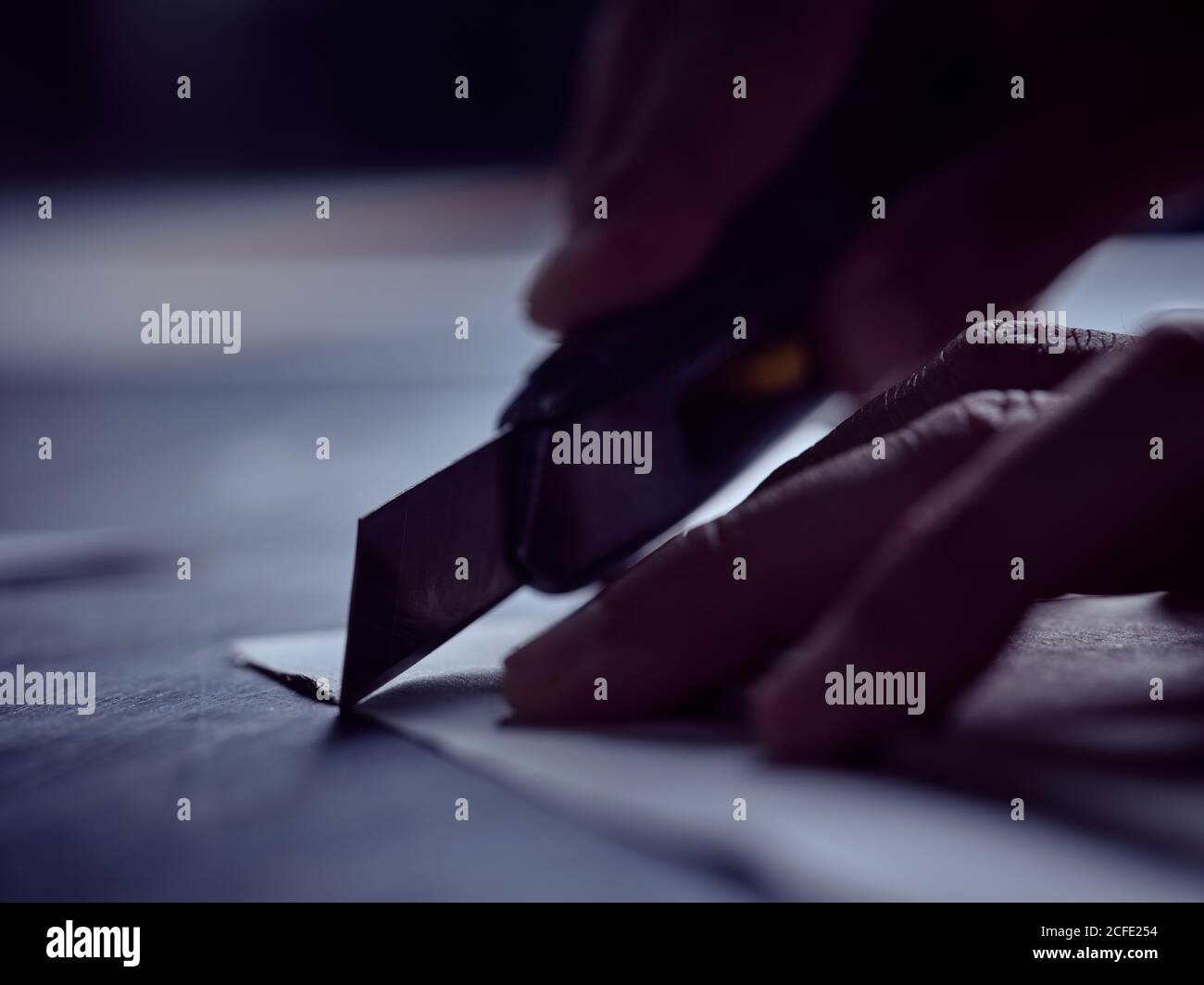 Crop professional man cutting paper sheets with special sharp knife on ...