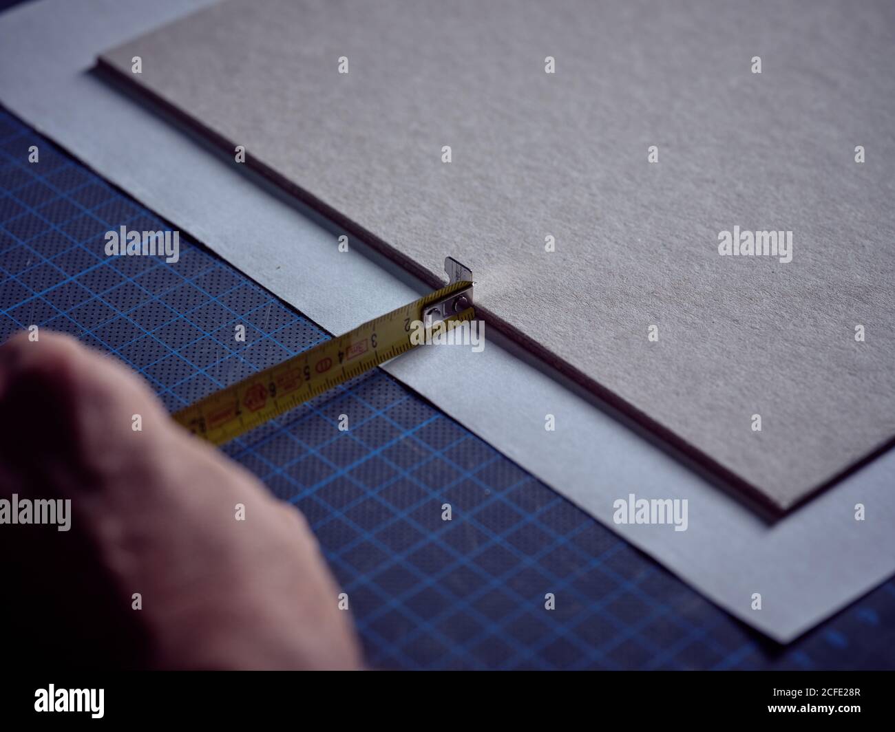 Hand of craftsman using steel ruler to measure paper border for folding ...