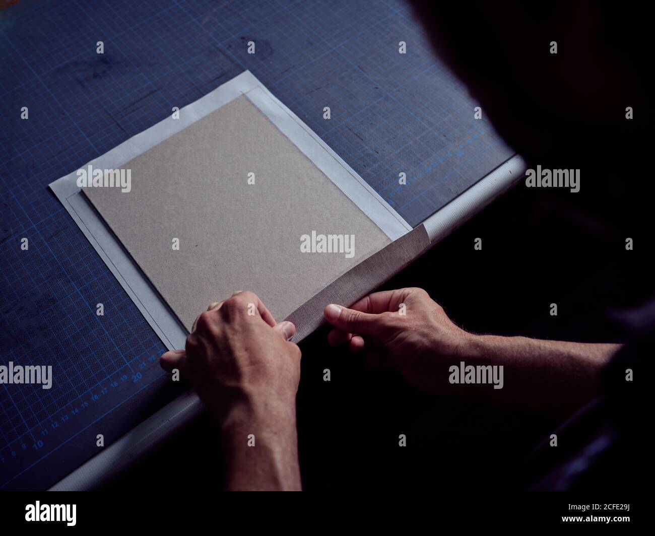 Bookbinder imposing fabric on cover for book Stock Photo - Alamy