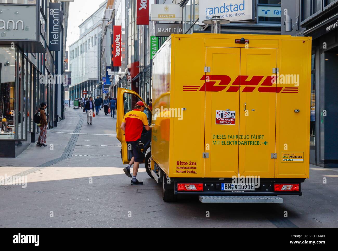 DHL parcel car in the pedestrian zone in front of shops and stores ...