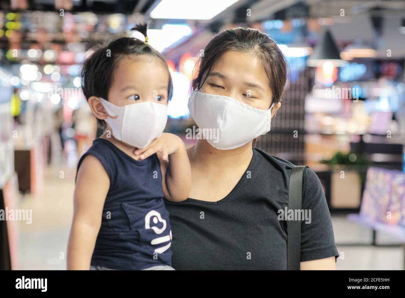 Mother carrying little boy shopping in supermarket wear n95 mask ...