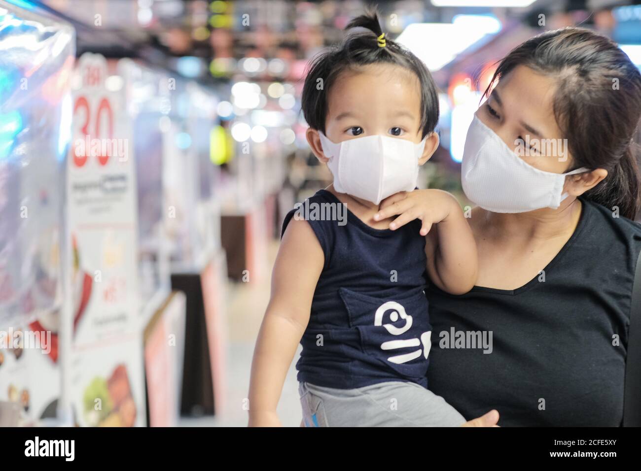 Mother carrying little boy shopping in supermarket wear n95 mask ...