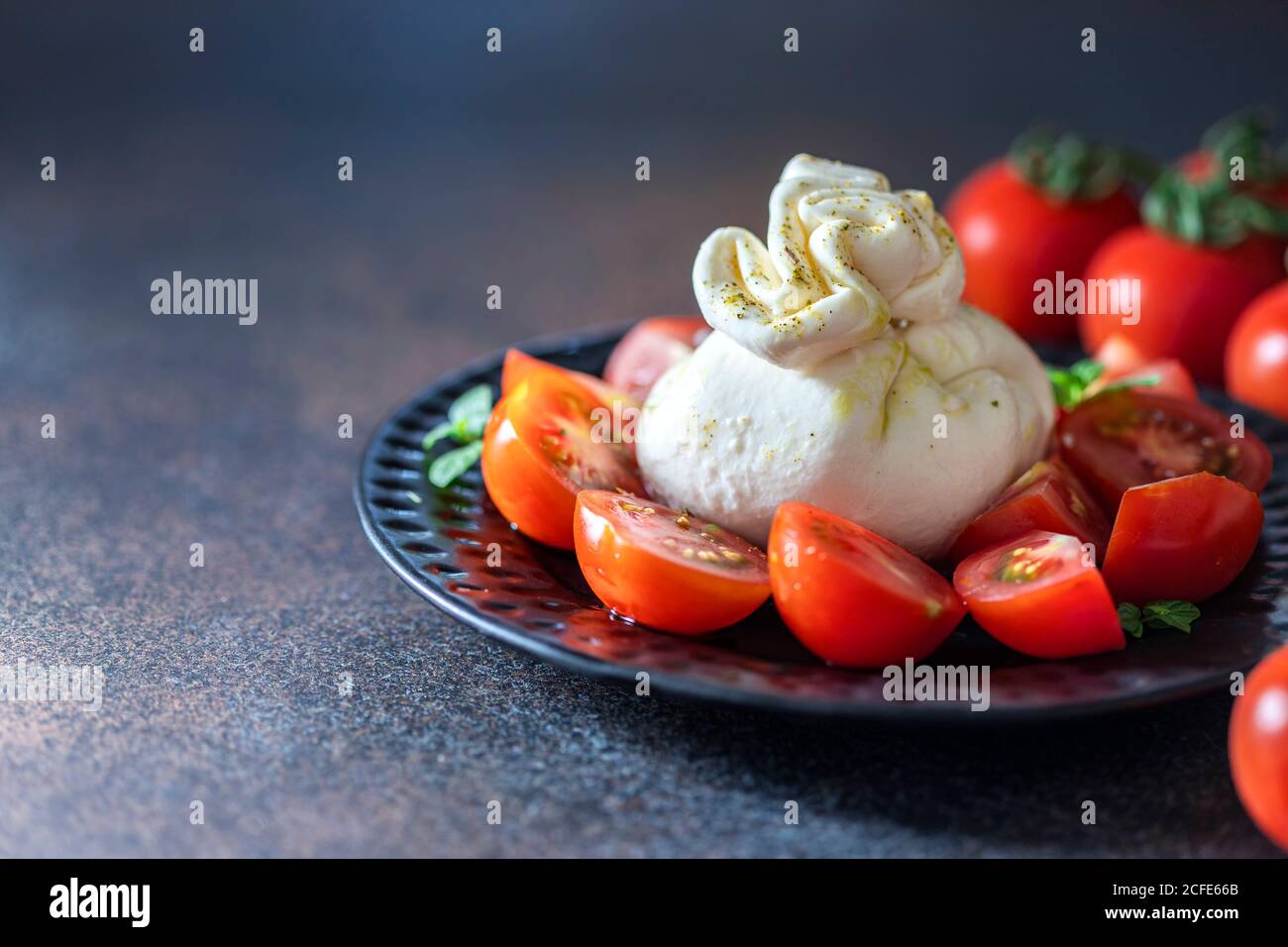 Traditional italian food barrata and tomatoes on a dark background ...