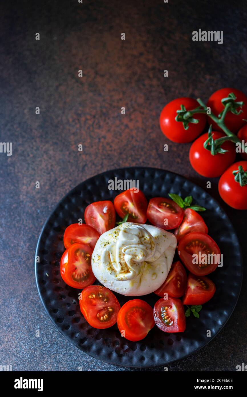 Traditional italian food barrata and tomatoes on a dark background ...