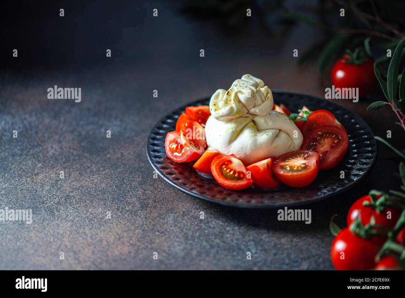 Traditional italian food barrata and tomatoes on a dark background ...