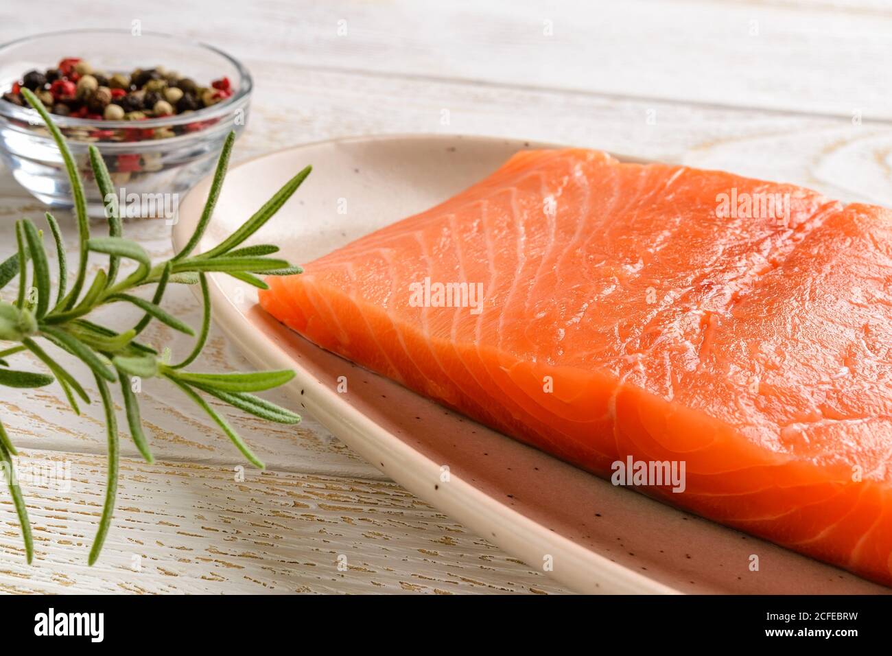 Fresh raw chilled salmon fillet a plate, pepper grains and rosemary on ...