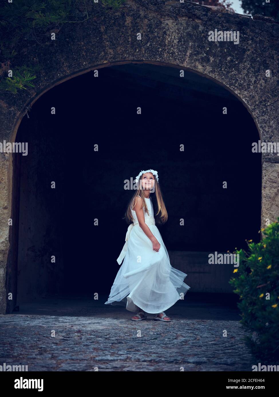 Adorable little girl in airy long white dress and flower headband ...