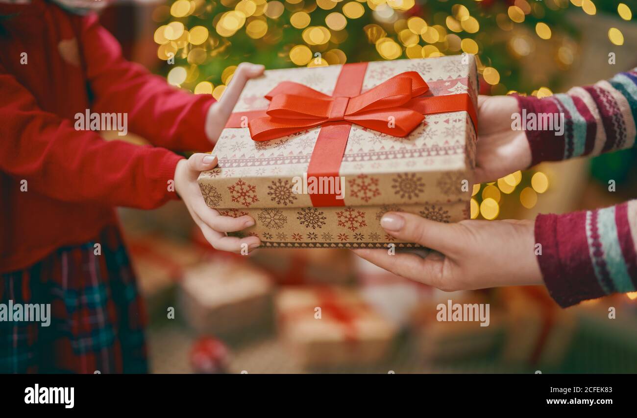 Merry Christmas and Happy Holidays! Hands of parent giving a x-mas gift ...