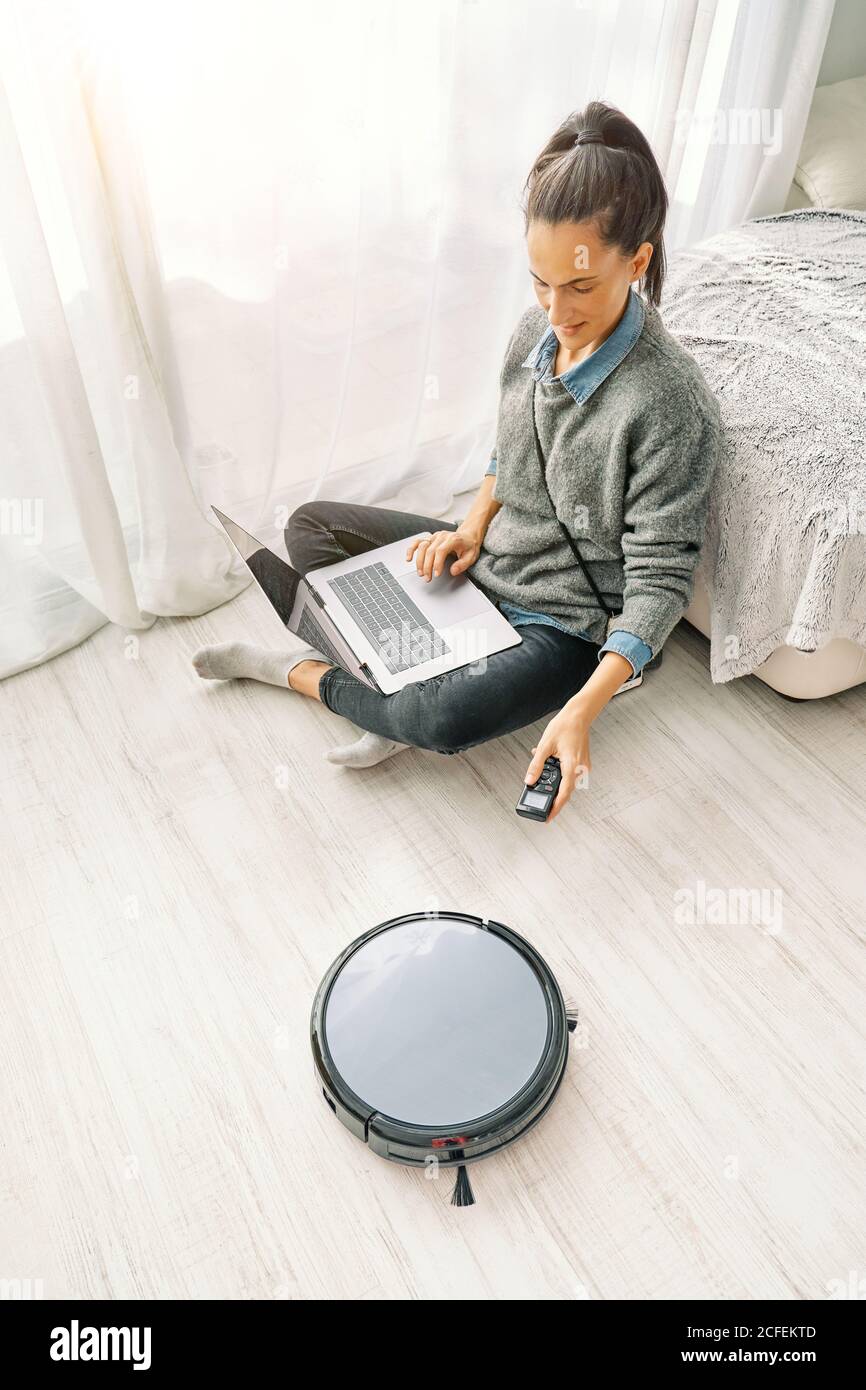 From above Woman in casual clothes using remote control for robotic ...