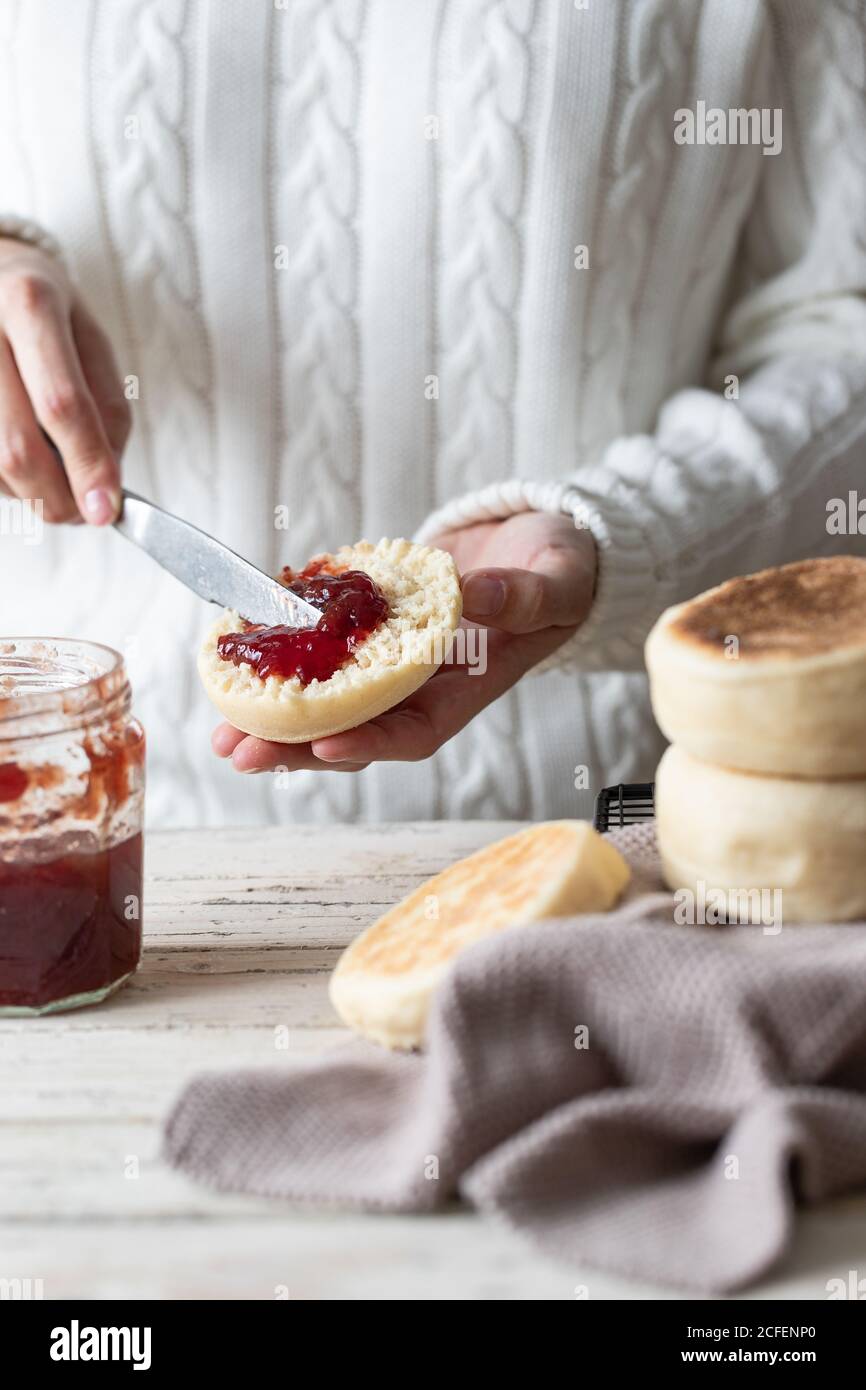 Closeup of crop person spreading yummy red berry jam on cut fresh ...