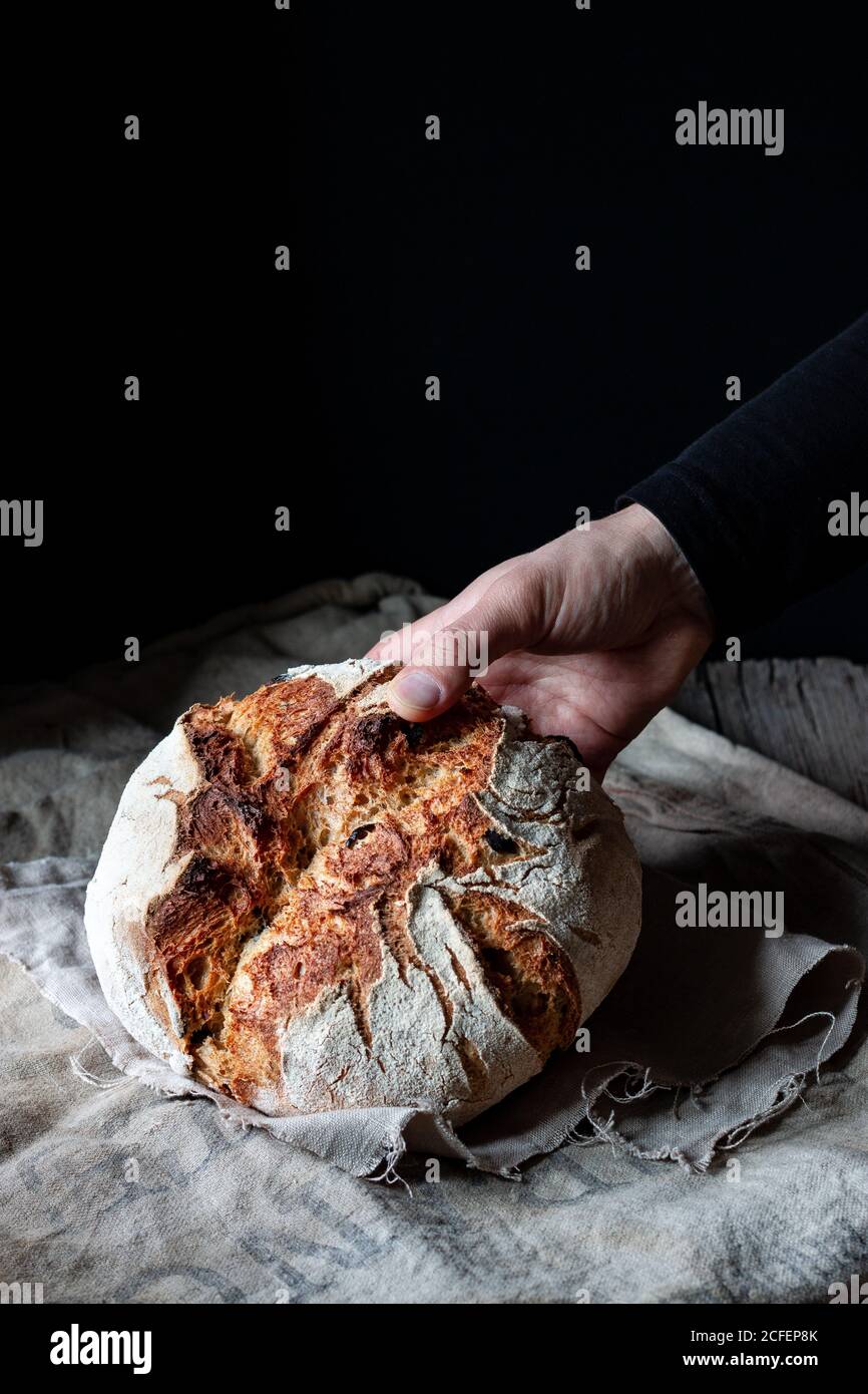 unrecognizable person putting loaf of payes bread on linen cloth on ...