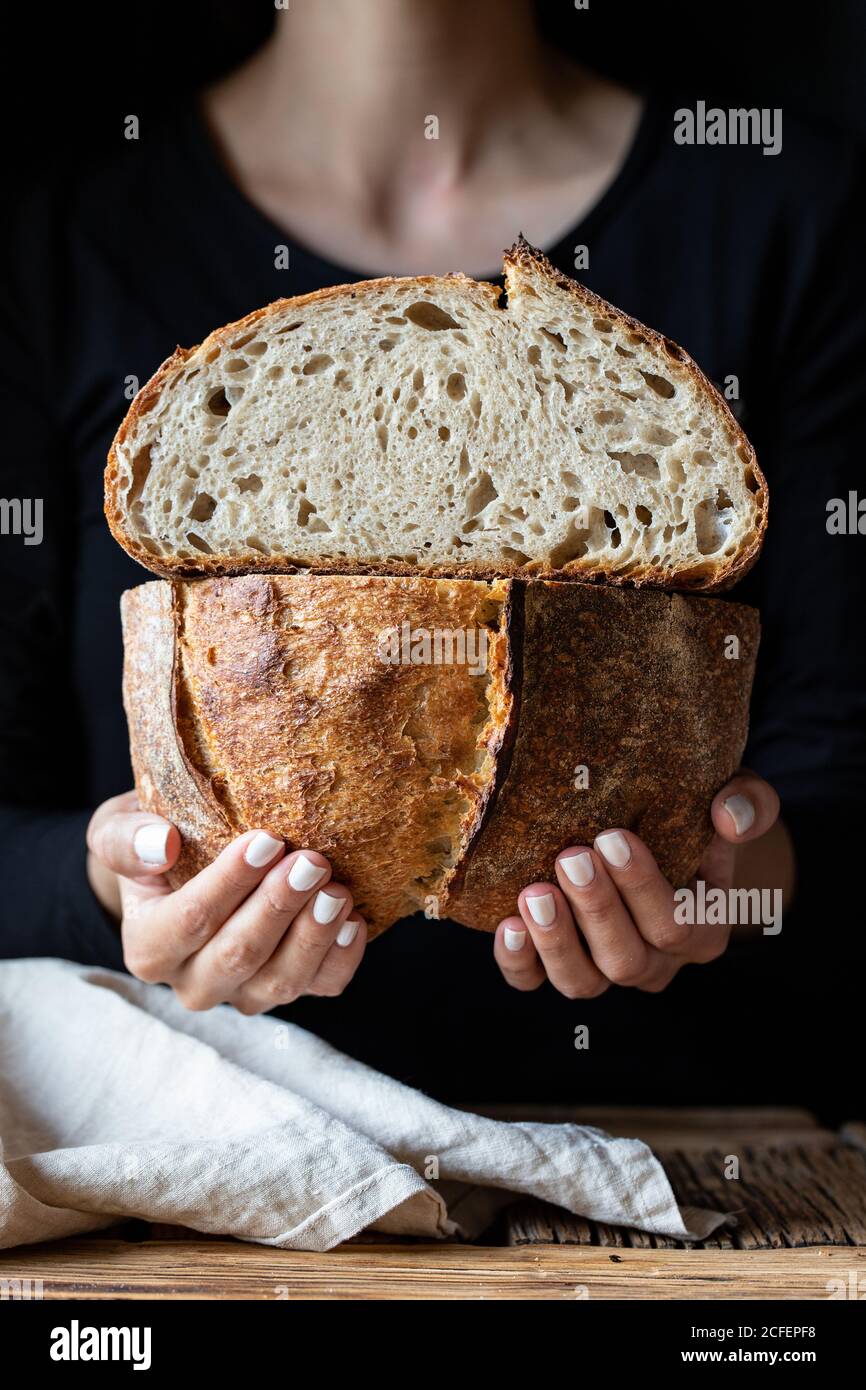unrecognizable person showing fresh halved bread with seeds against ...