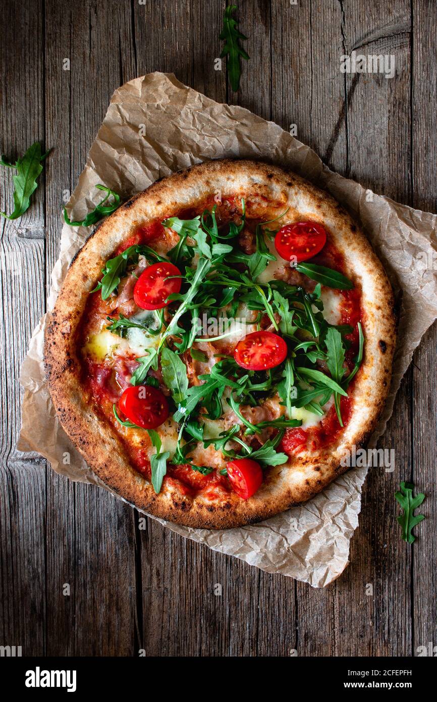 From above delicious pizza with tomato and salad placed with checkered ...