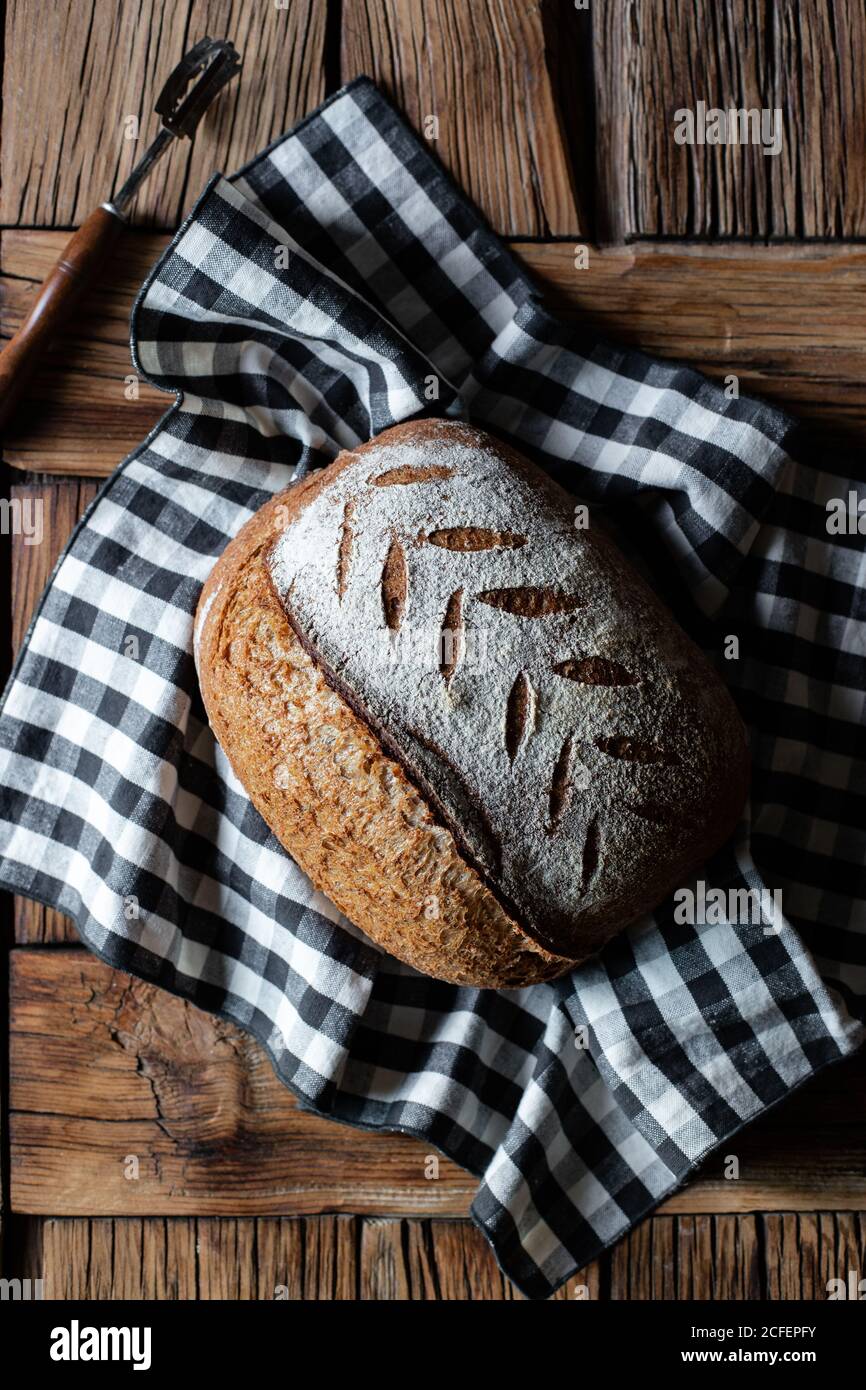 Top view of loaf of fresh spelt bread placed on checkered napkin near ...
