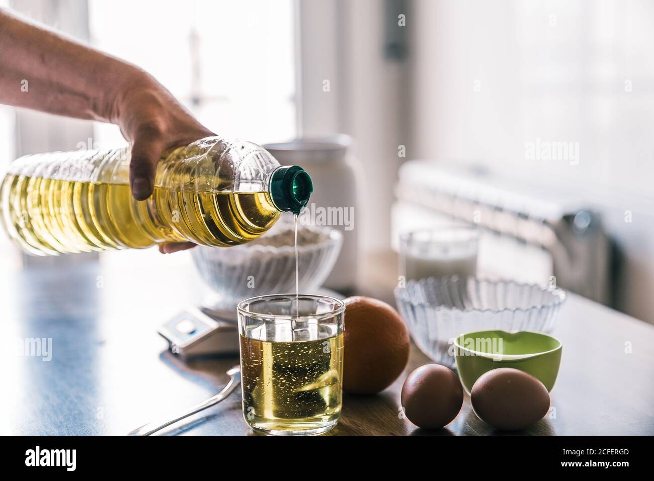 Crop anonymous female pouring vegetable oil into measure glass placed ...