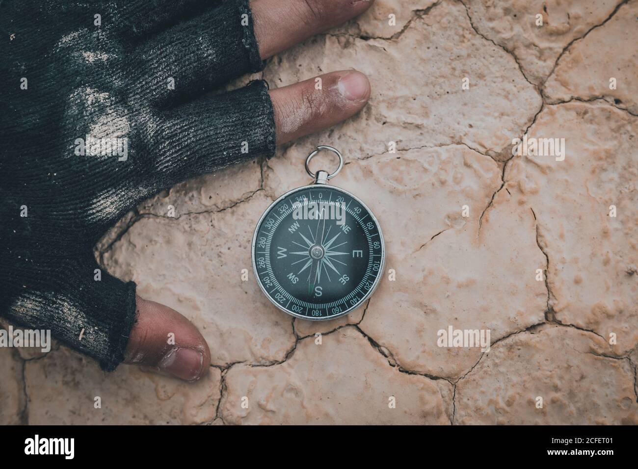 Compass near hand on dry desert area Stock Photo - Alamy