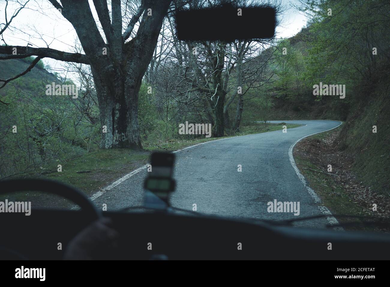 View from inside car of empty road of rural area in overcast weather ...