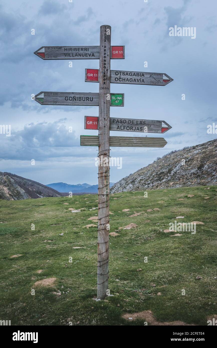 Shabby wooden post with direction signs located on grassy hillside ...