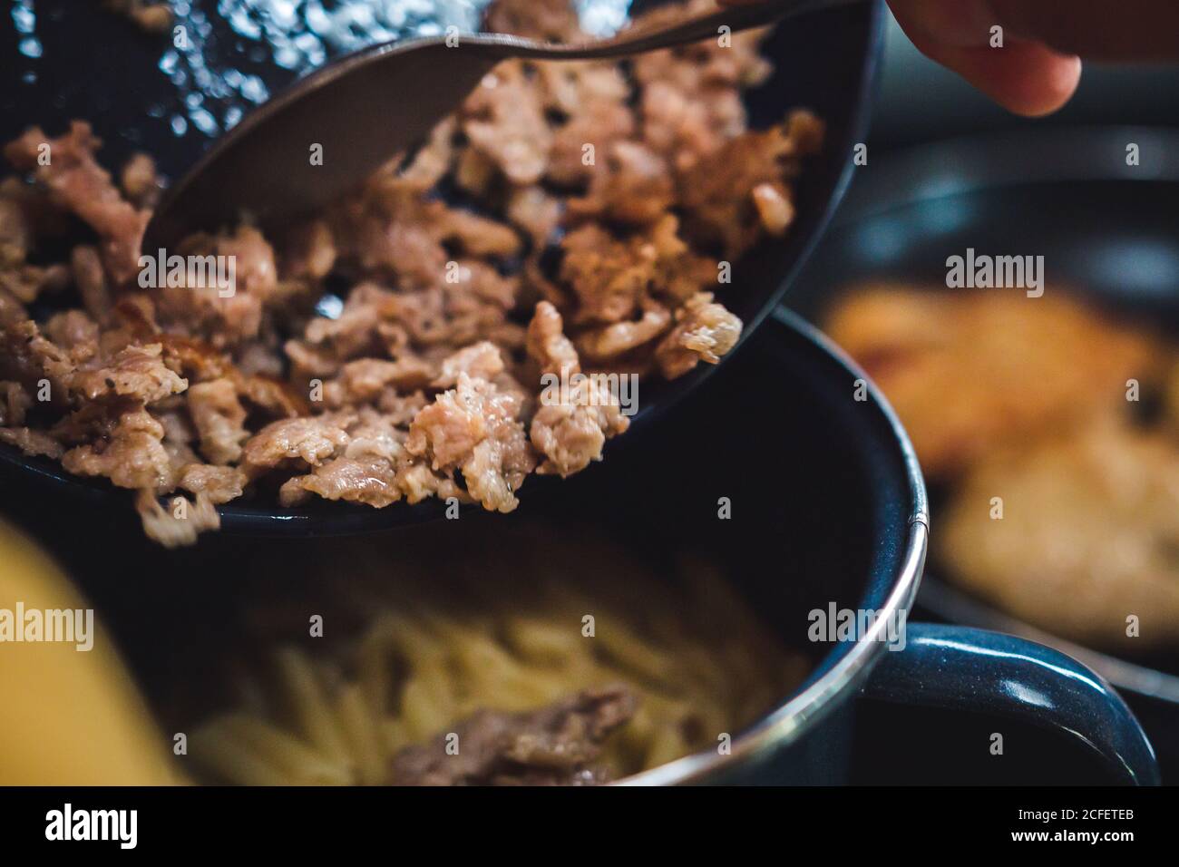 Hand of anonymous person pressing ground meat with fork on frying pan ...