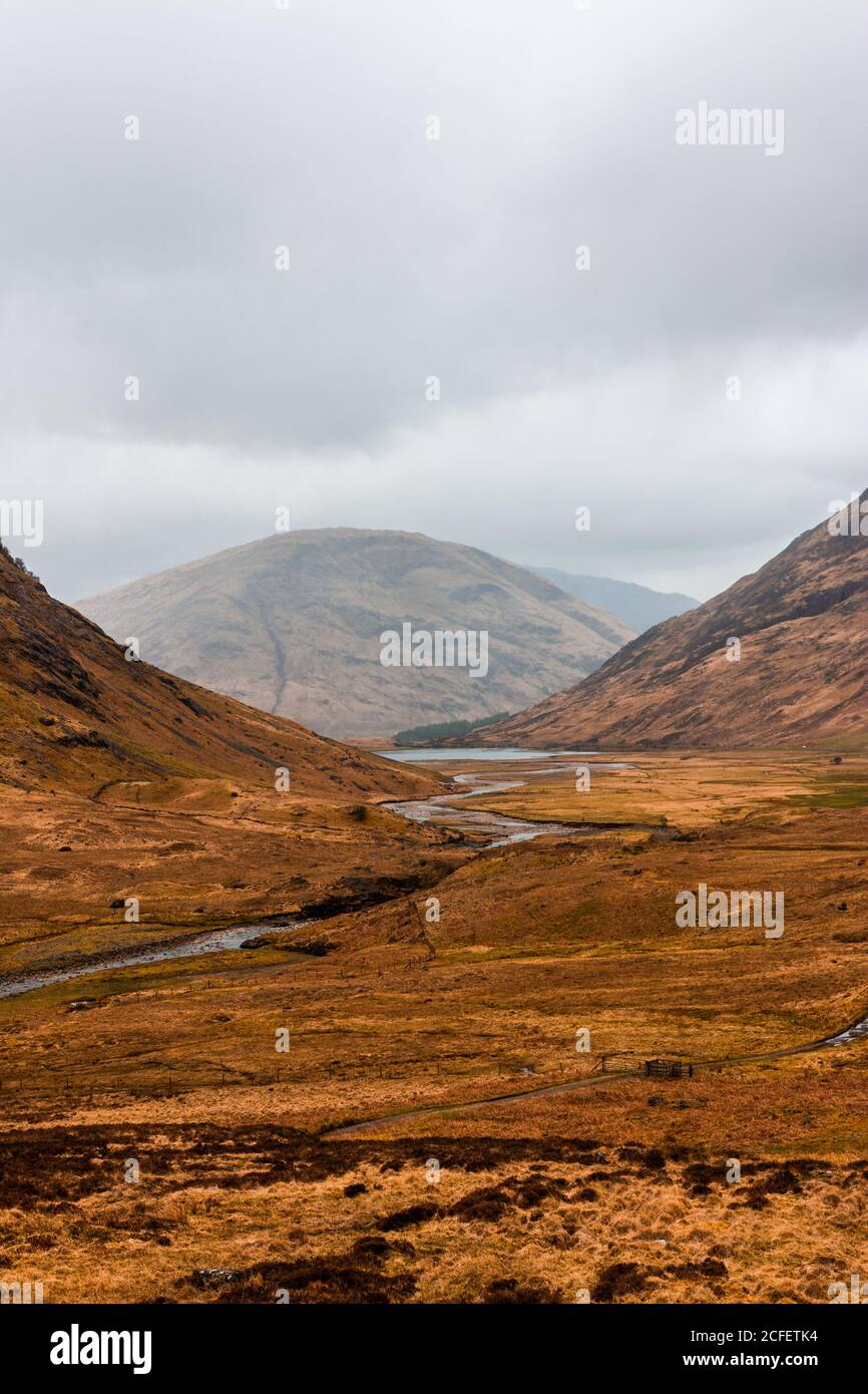 Narrow curvy road running through hilly terrain with dry grass among ...