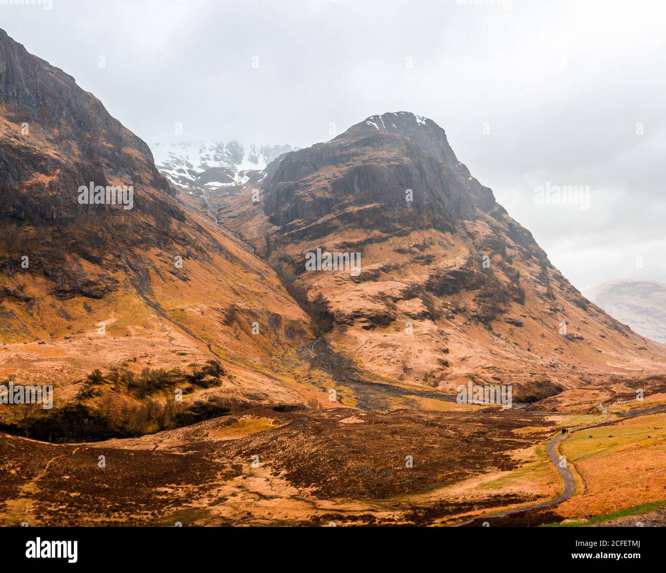 Narrow curvy road running through hilly terrain with dry grass among ...