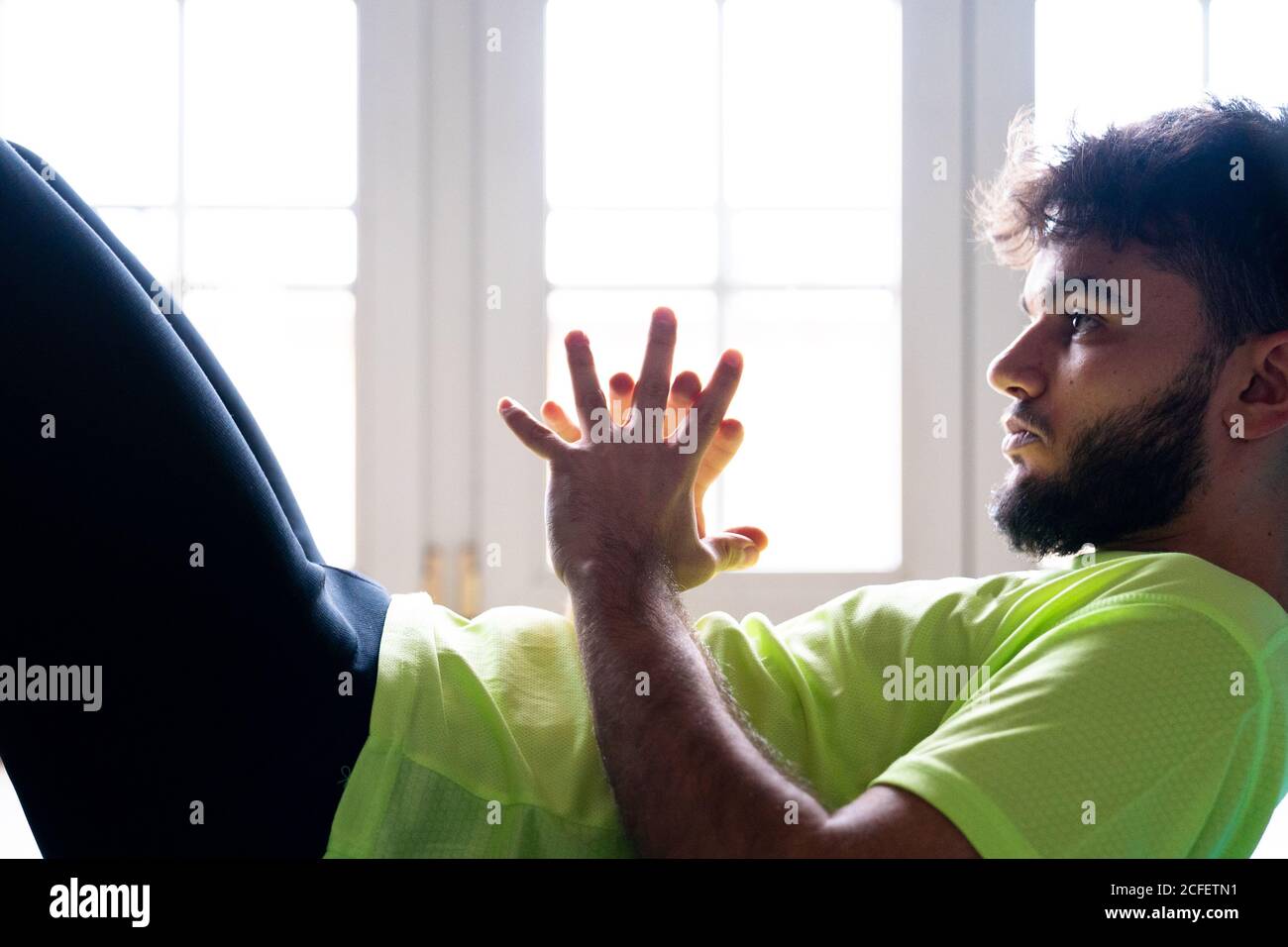 High angle side view of determined male athlete in sportswear doing abs ...