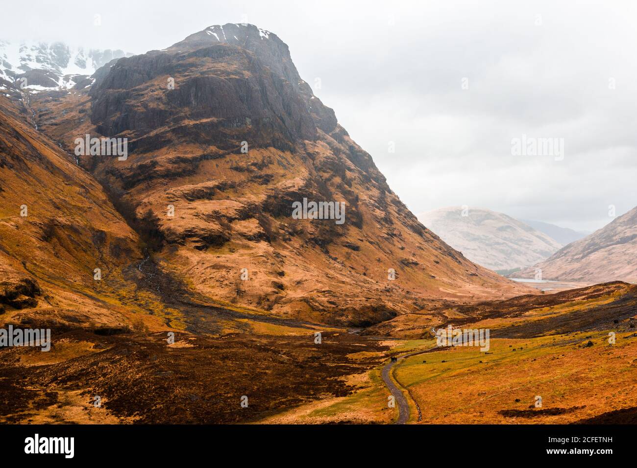 Narrow curvy road running through hilly terrain with dry grass among ...