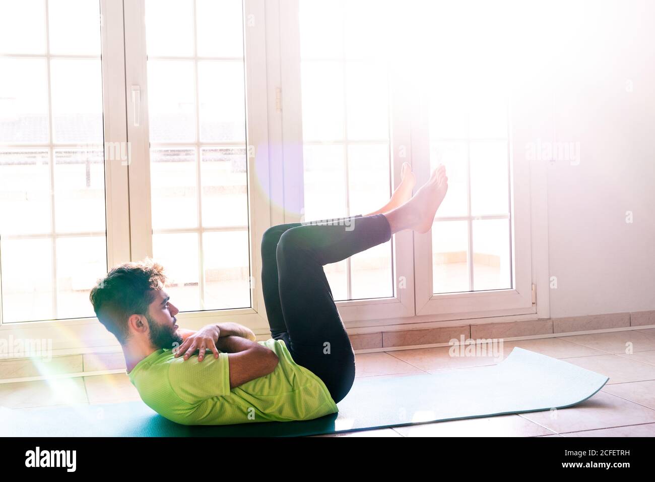 High angle side view of determined male athlete in sportswear doing abs ...